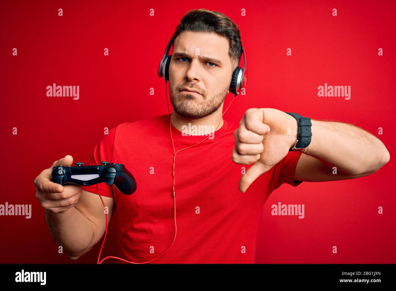 Young gamer man with blue eyes playing video games using gamepad ...