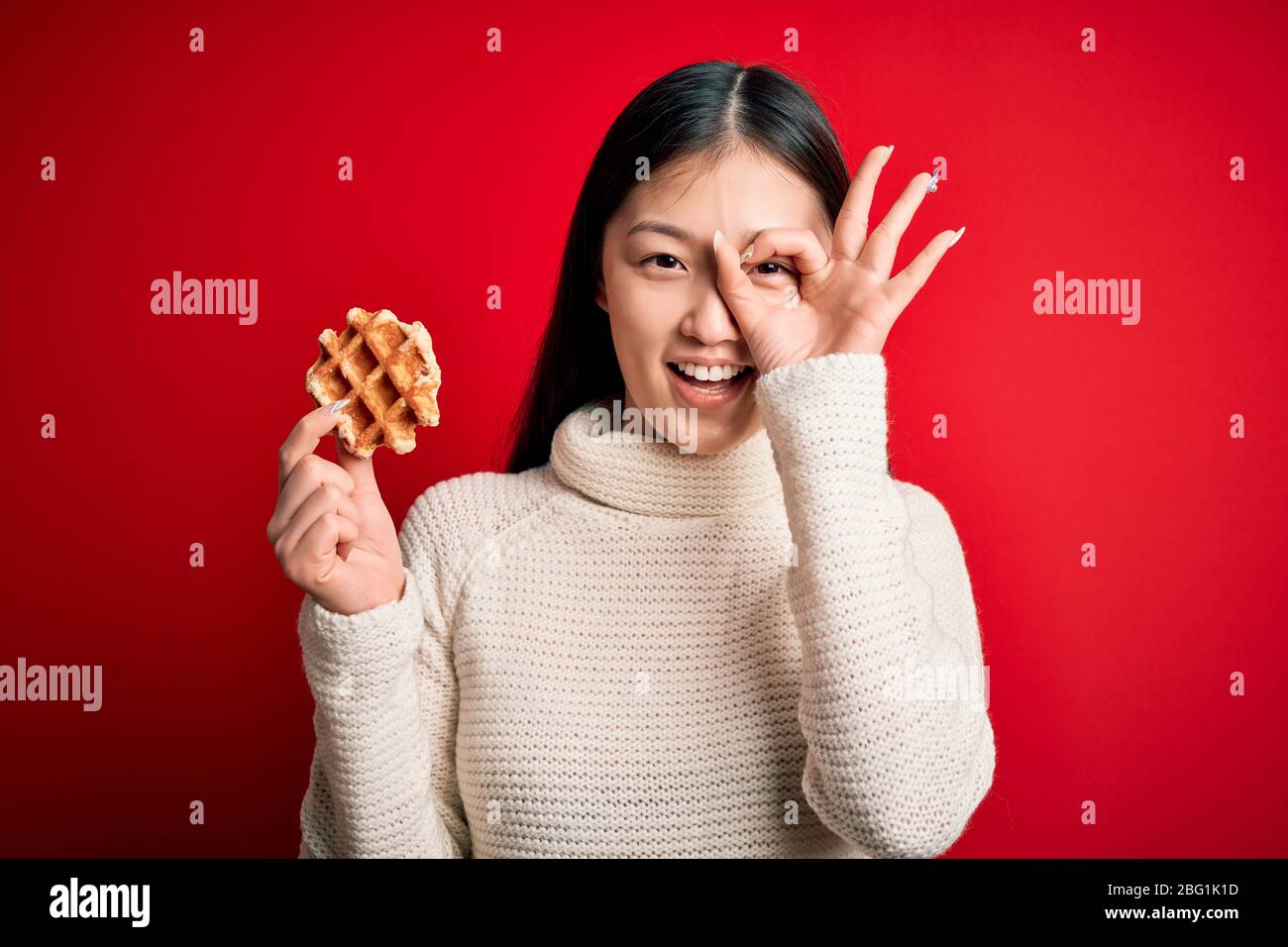 Young asian woman eating sweet and tasty belgian waffle over red ...