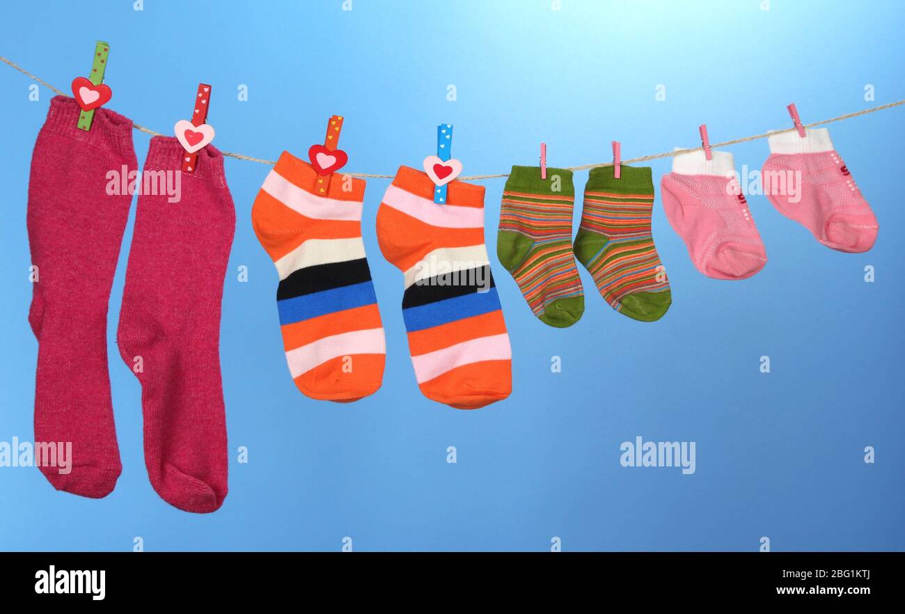 Colorful socks hanging on clothesline, on color background Stock Photo ...