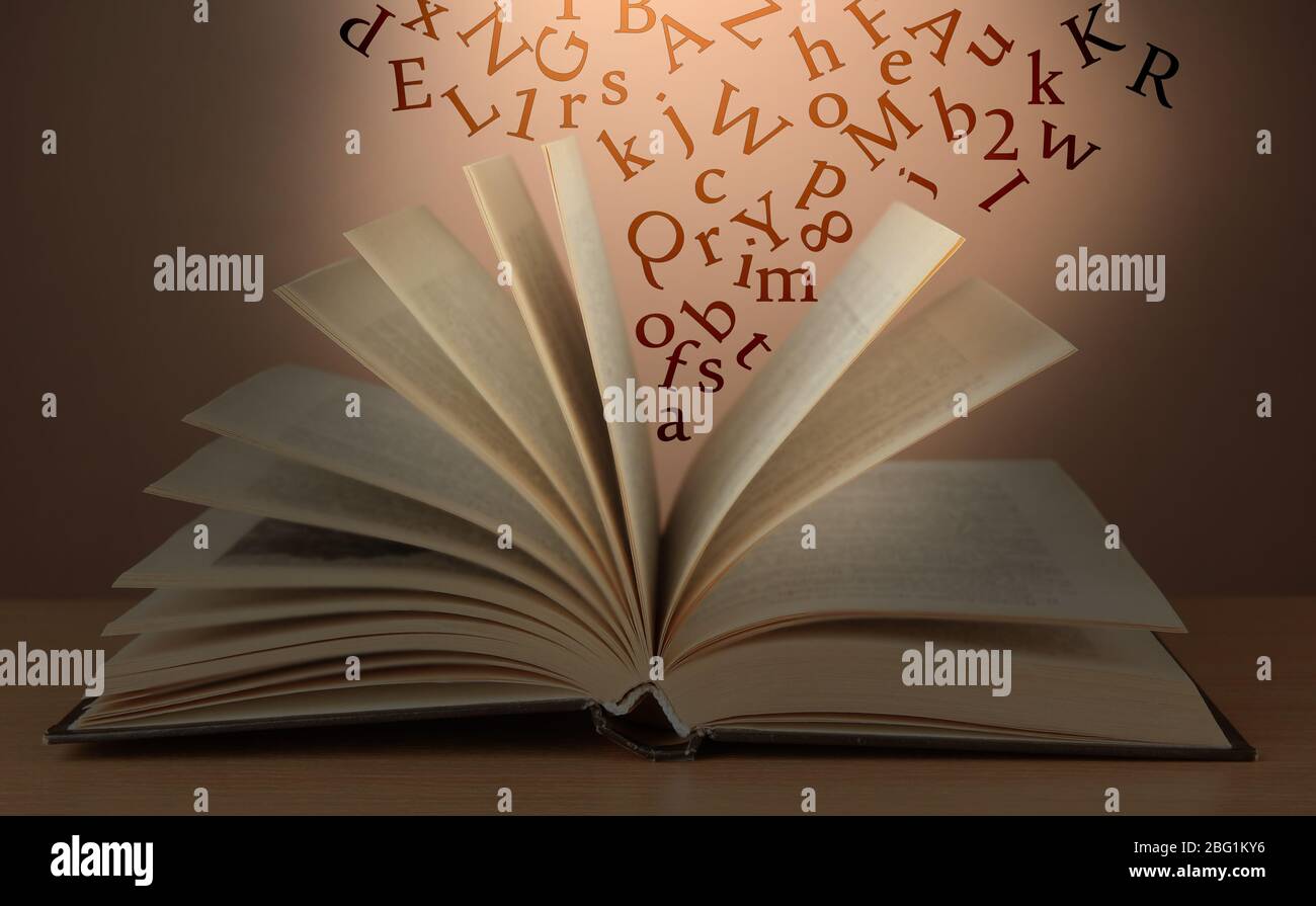 Opened book with letters flying out of it on brown background Stock ...