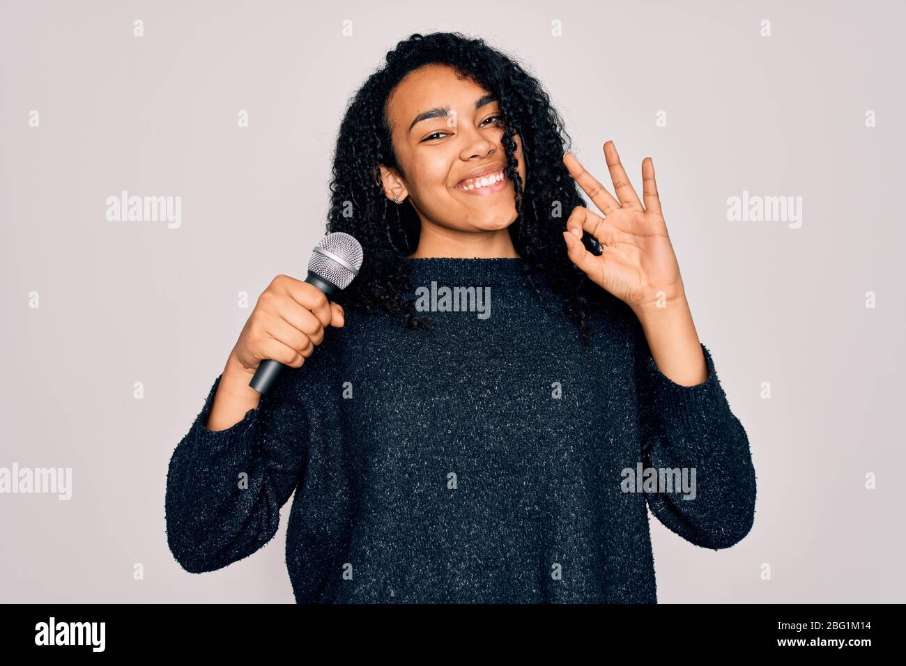 Young african american curly singer woman singing using microphone over ...
