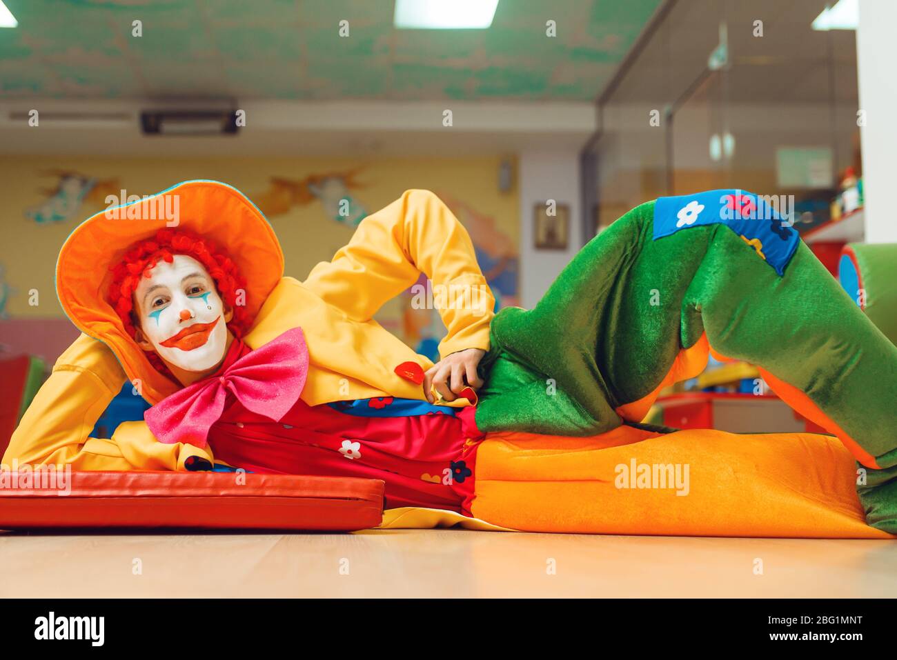 Funny clown in costume lying on the floor Stock Photo - Alamy