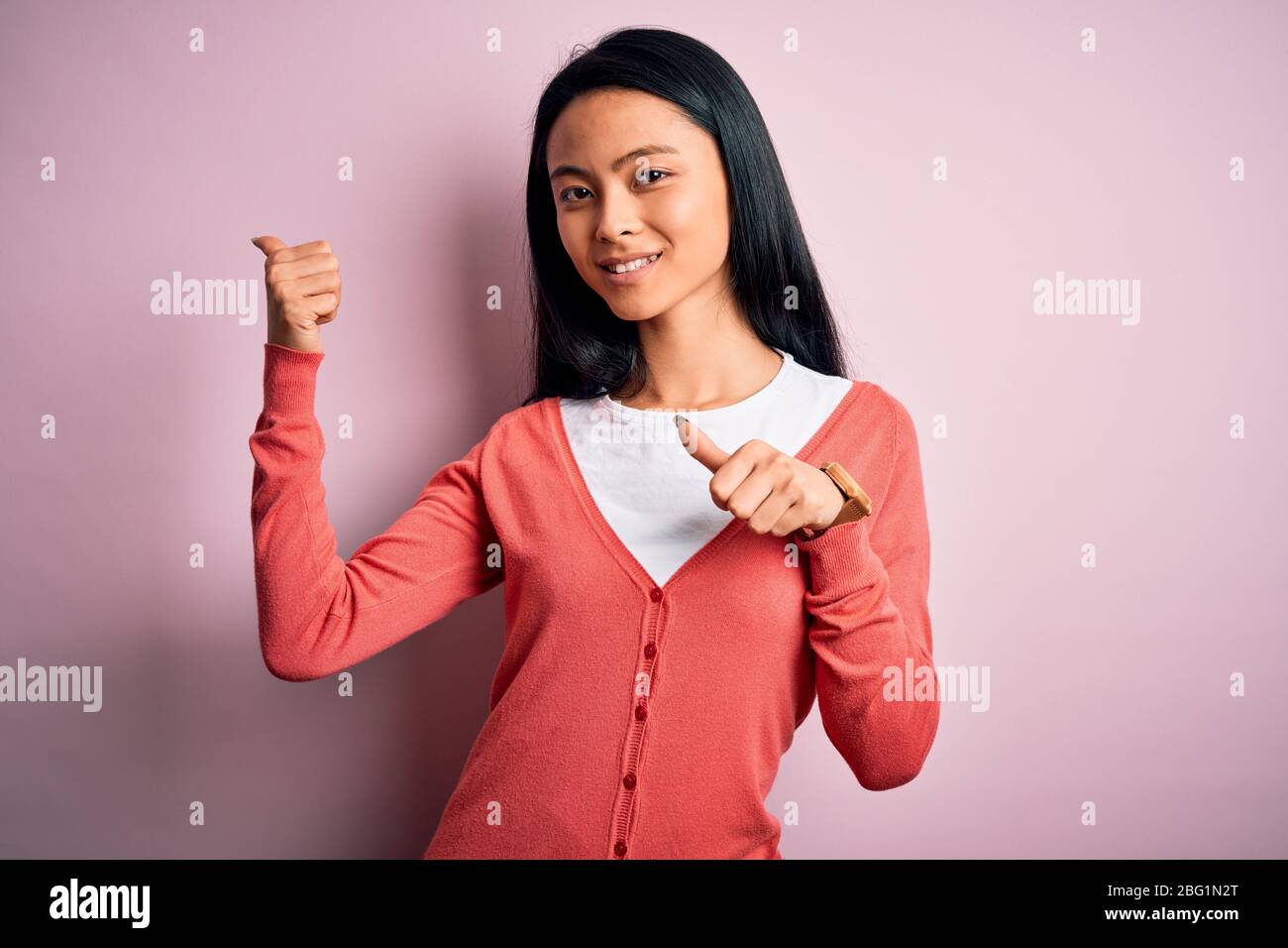 Young beautiful chinese woman wearing casual sweater over isolated pink ...