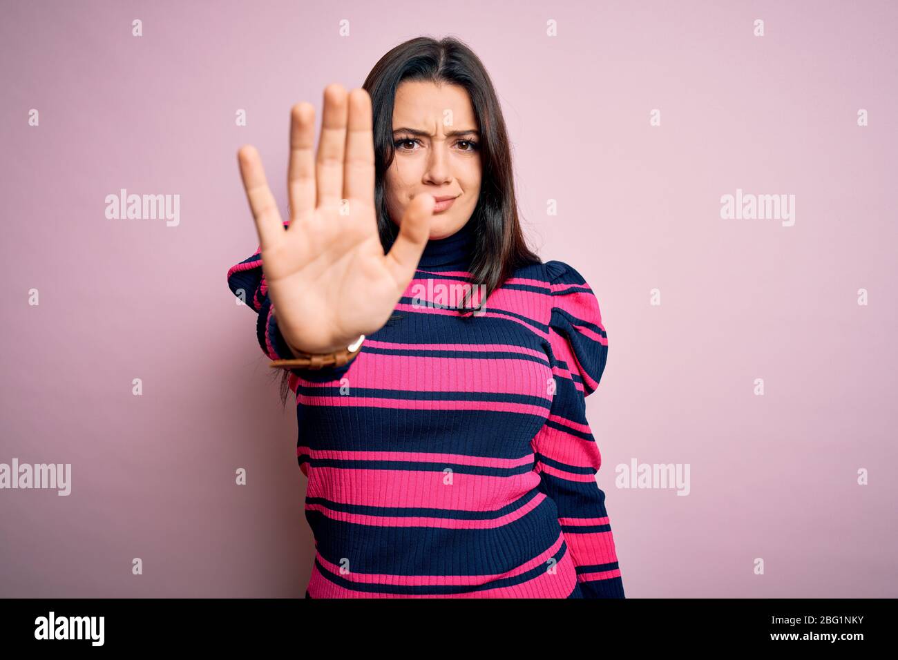 Young brunette elegant woman wearing striped shirt over pink isolated ...