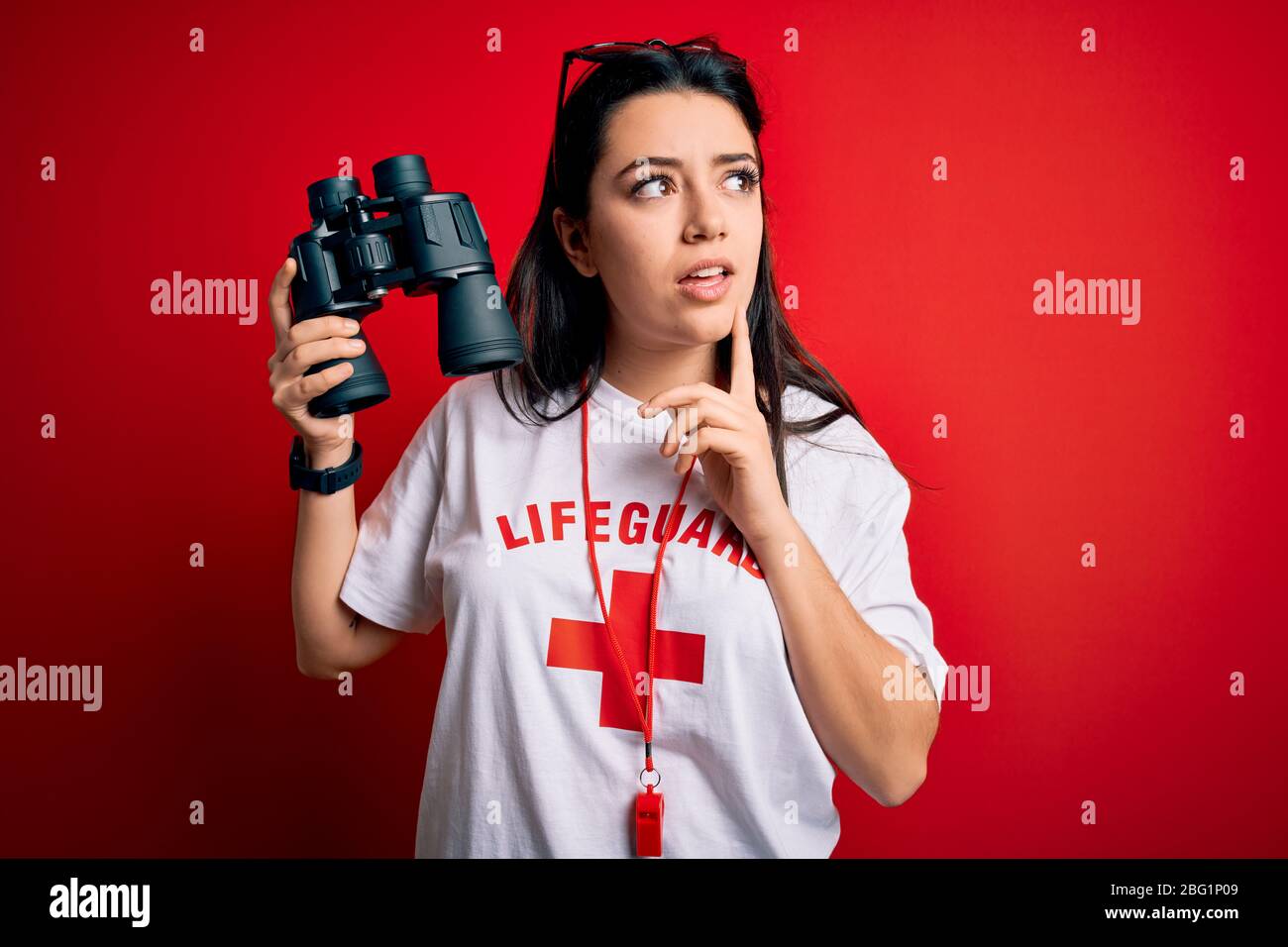 Young lifeguard woman wearing secury guard equipent holding binoculars ...