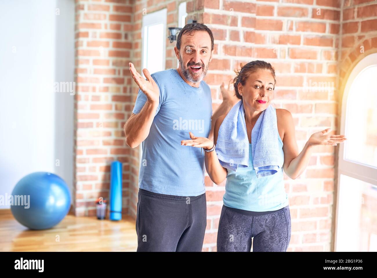 Middle age sporty couple standing before do exercise at gym clueless ...