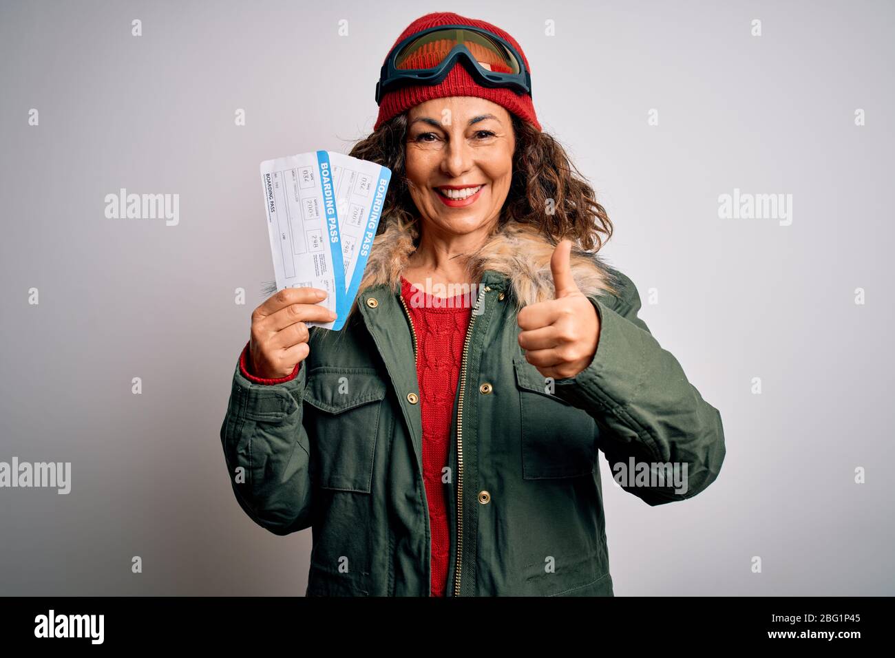 Middle age tourist woman wearing skier goggles holding airline boarding ...