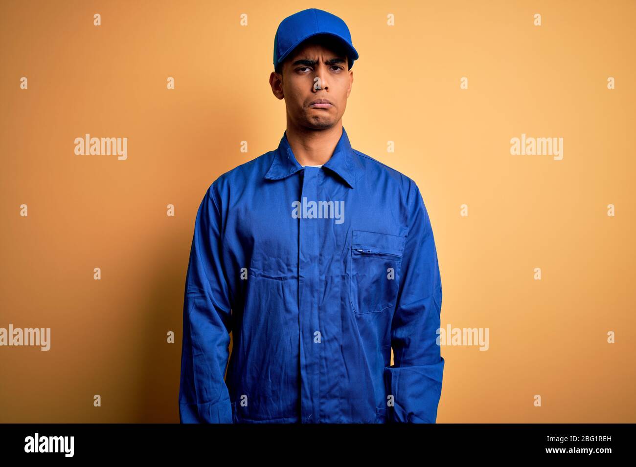 Young african american mechanic man wearing blue uniform and cap over ...