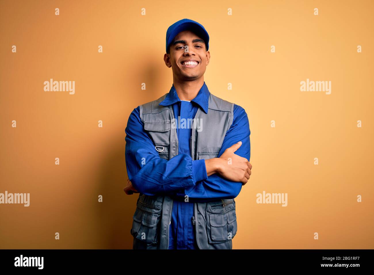 Young handsome african american handyman wearing worker uniform and cap ...