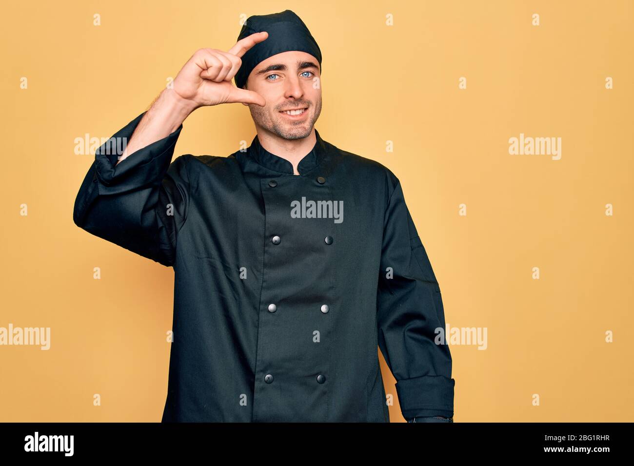 Young handsome cooker man with blue eyes wearing uniform and hat over ...