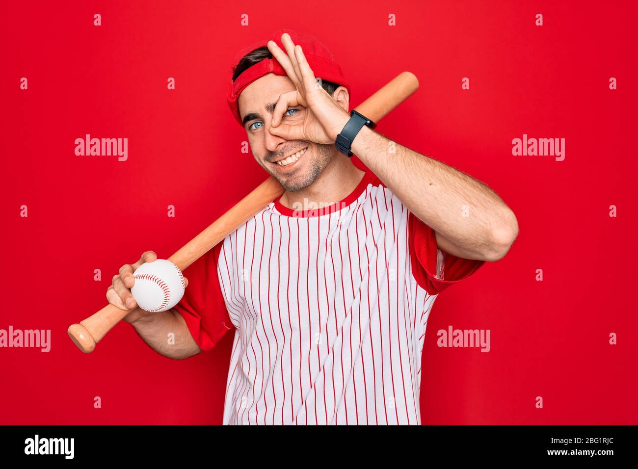 Young handsome sporty man with blue eyes playing baseball wearing cap ...