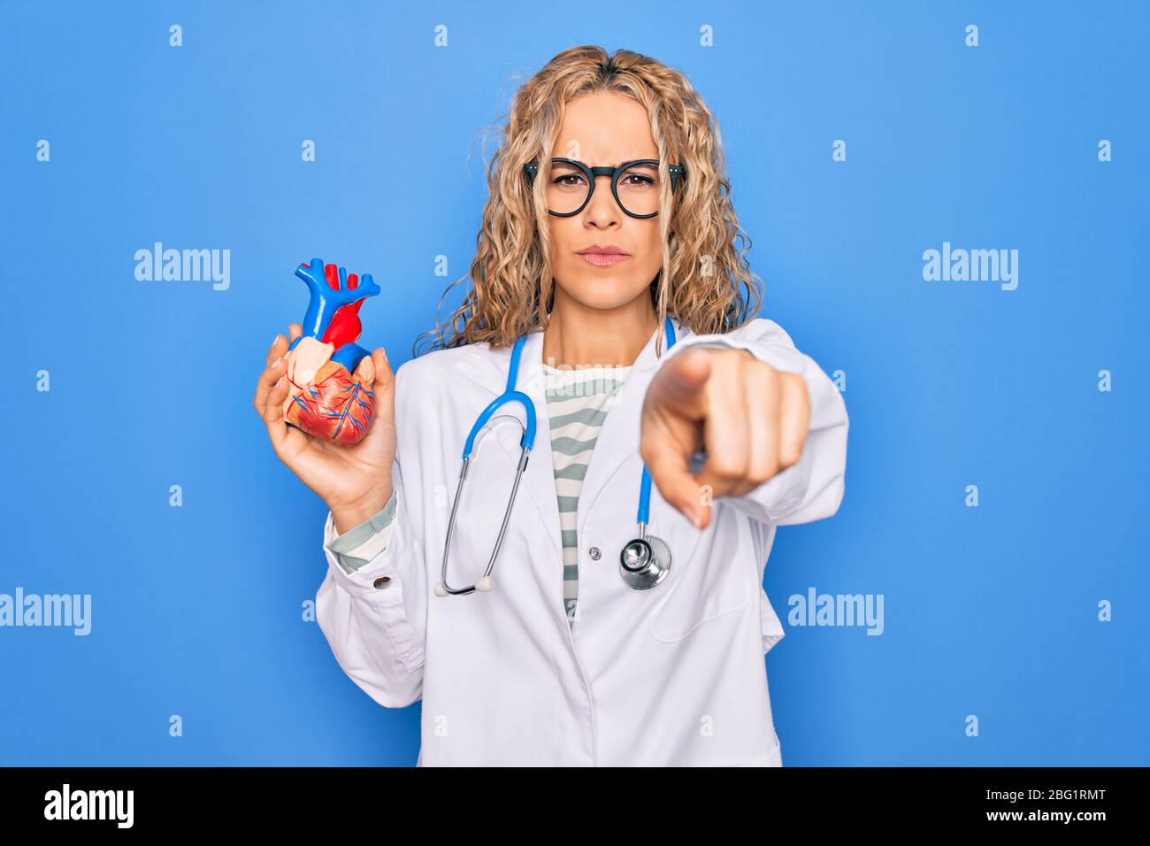 Young beautiful blonde cardiologist woman wearing stethoscope holding ...