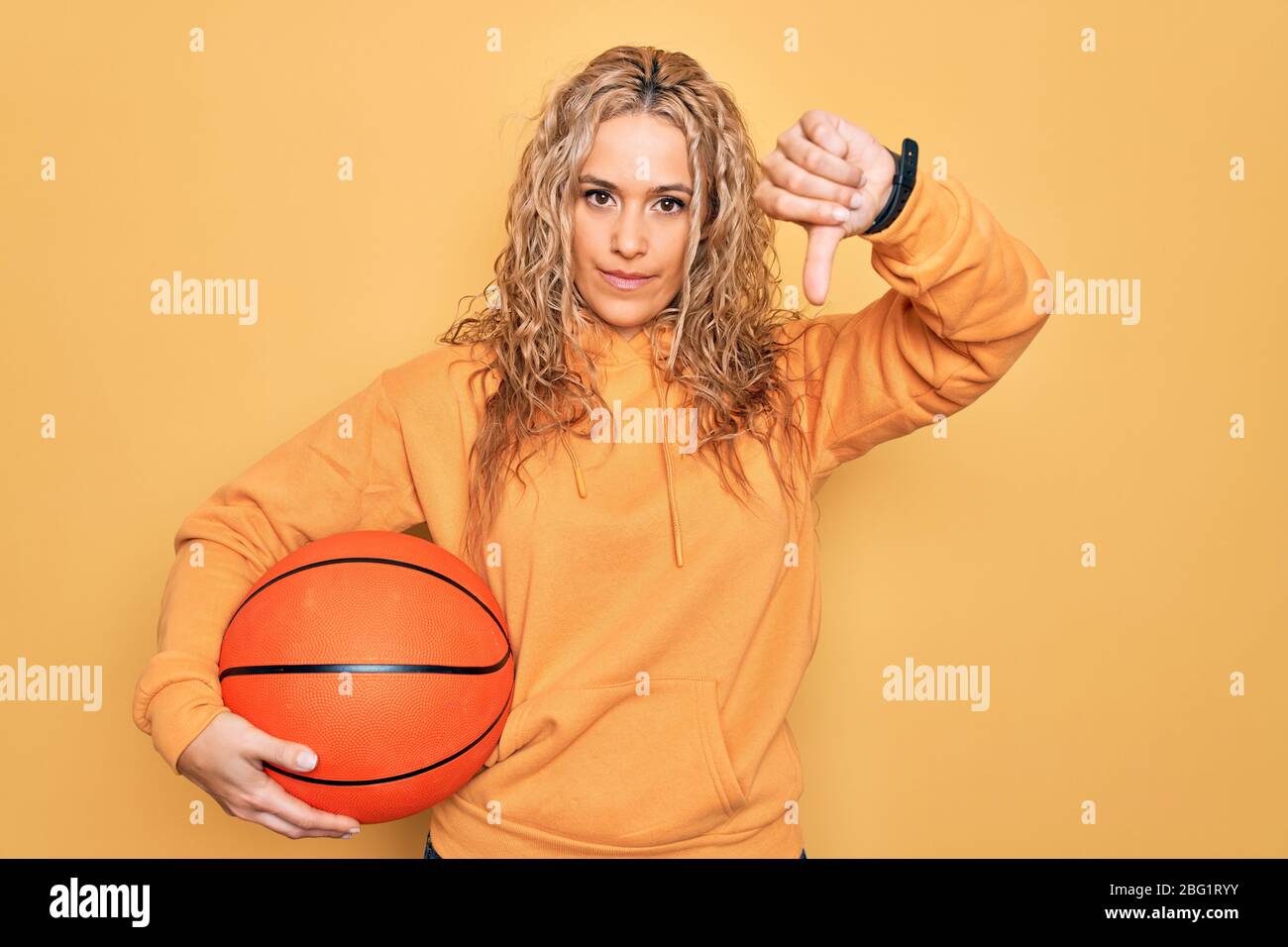 Beautiful blonde sportswoman doing sport holding basketball ball over ...
