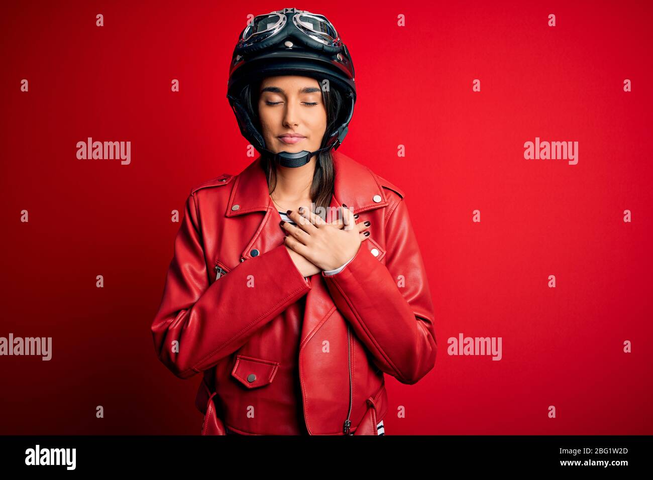 Young beautiful brunette motorcyclist woman wearing motorcycle helmet ...