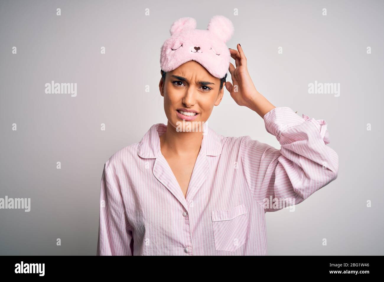 Young beautiful brunette woman wearing pajama and sleep mask over white ...