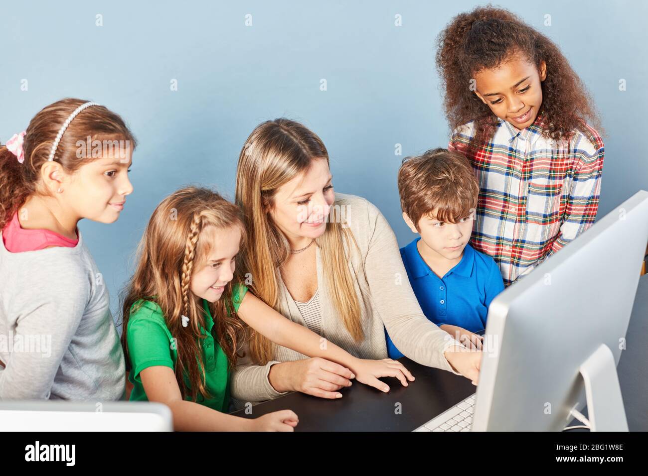 Woman at the computer as a teacher in elementary school gives computer ...