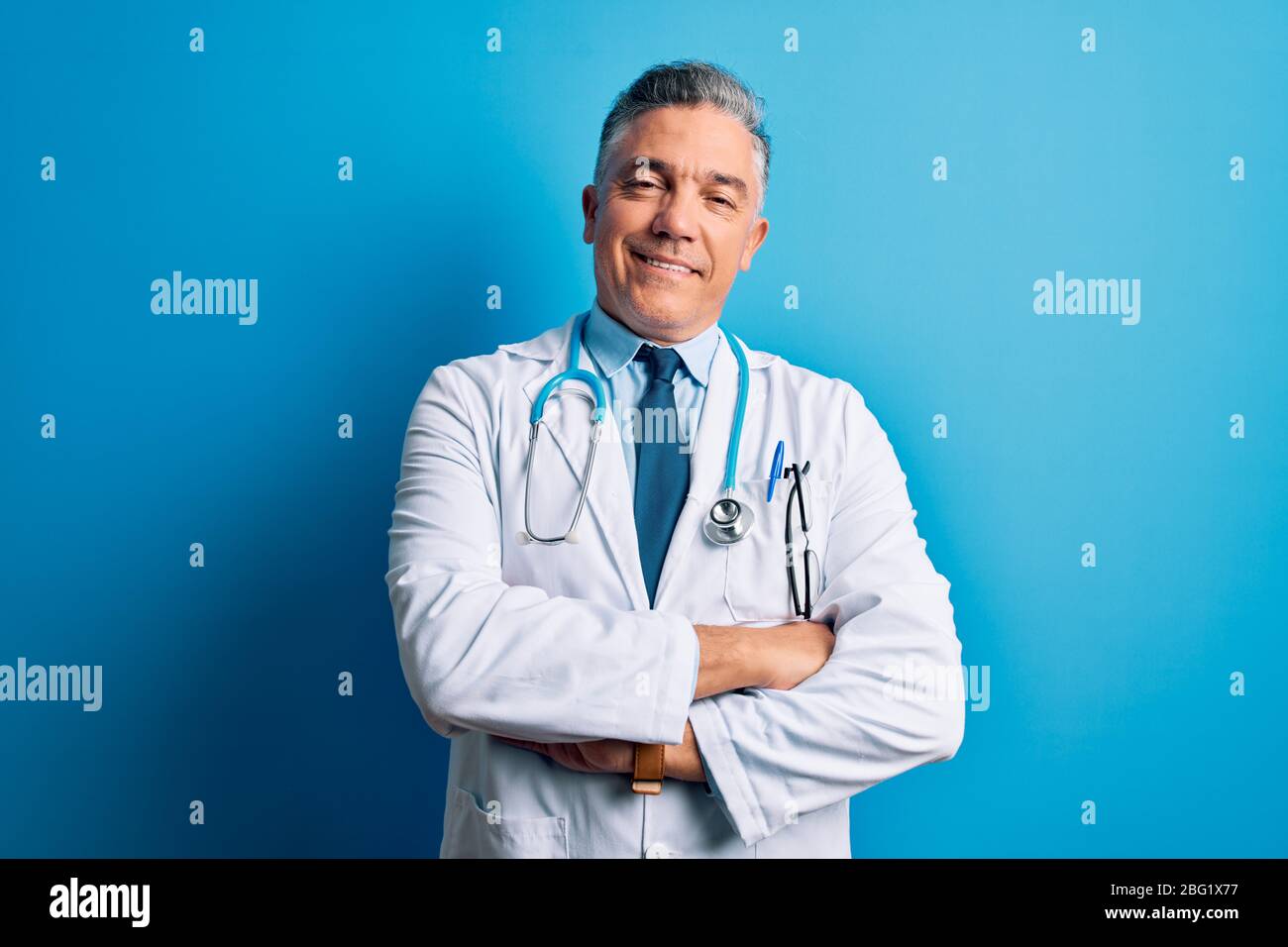 Middle age handsome grey-haired doctor man wearing coat and blue ...