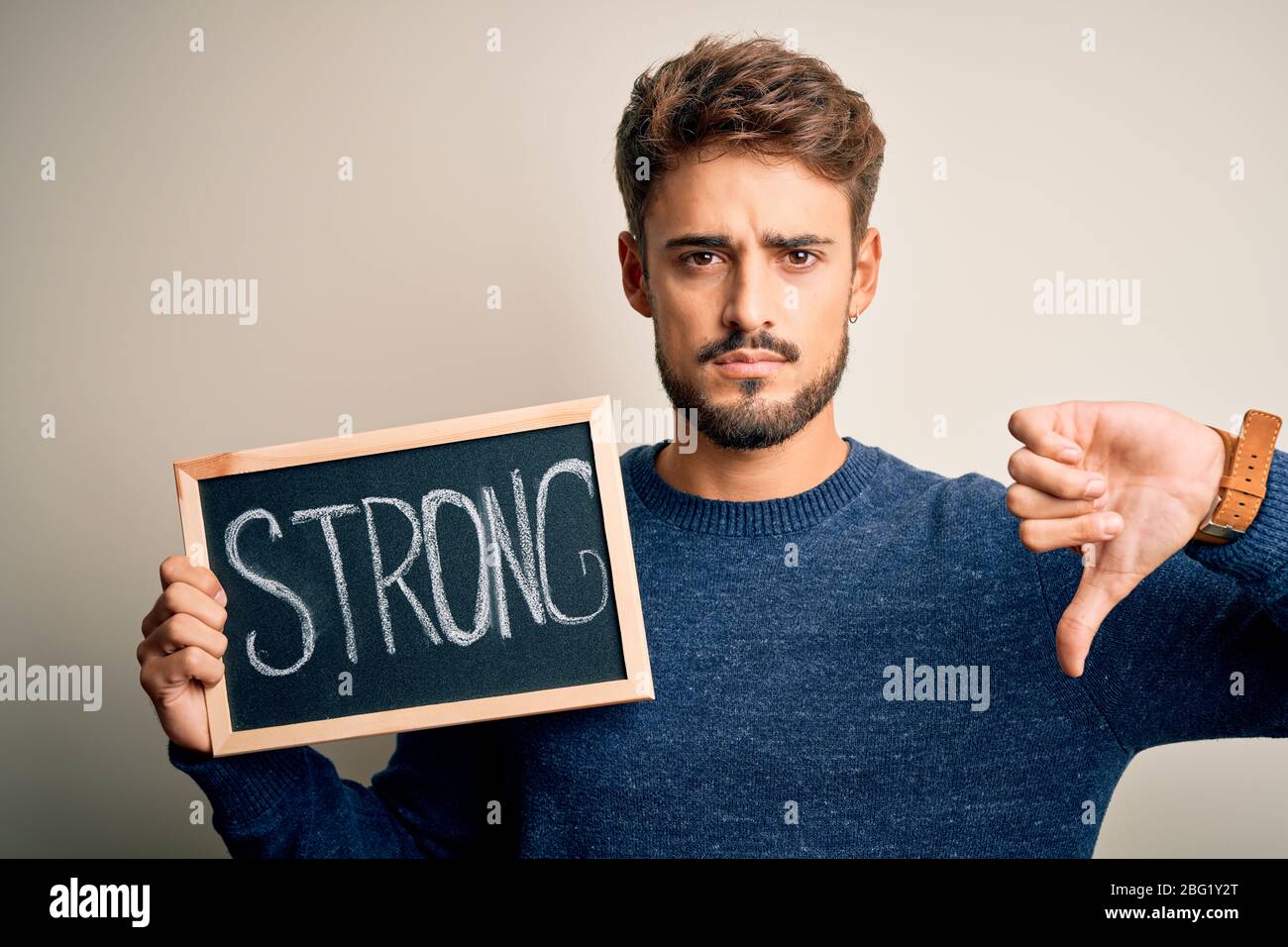 Young man holding blackboard with strong message standing over isolated ...