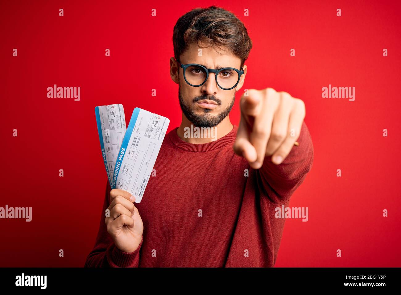 Young tourist man on vacation holding boarding pass standing over red ...