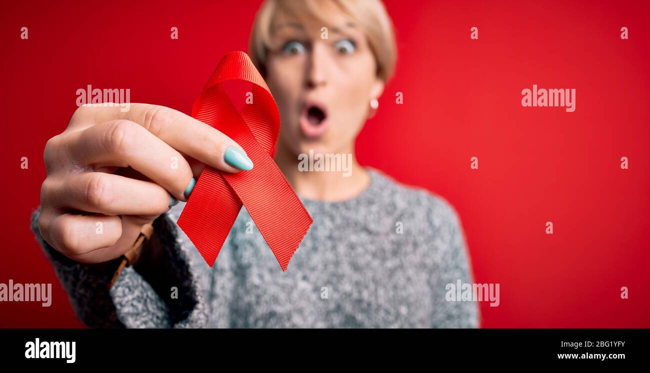 Young blonde woman with short hair holding hiv and aids awareness red ...