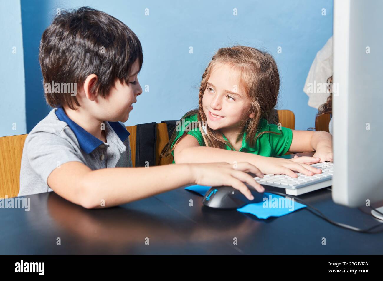 Two students are learning together at a computer in elementary school ...