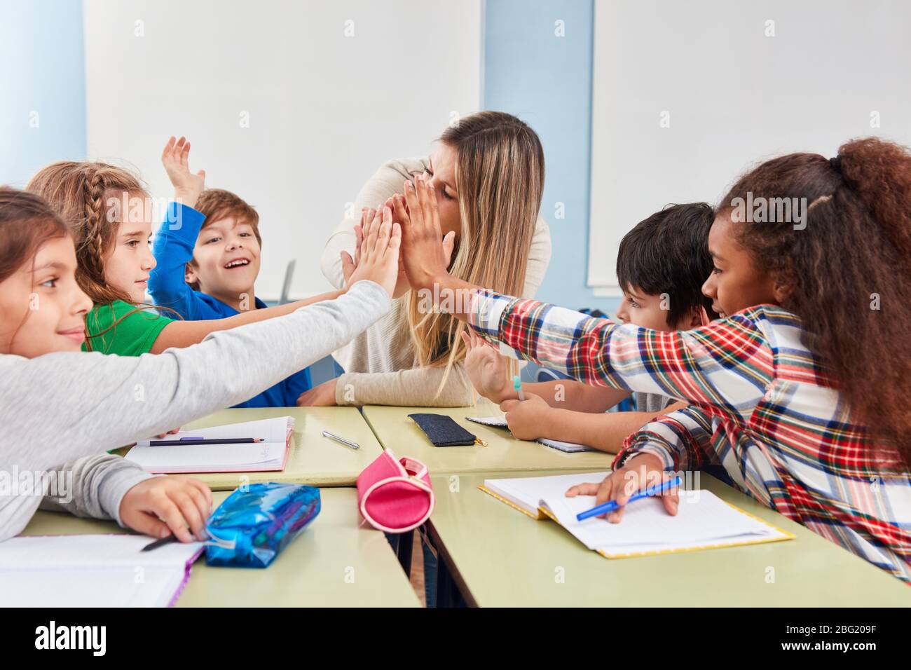 Group of students makes high five in the classroom of a primary school ...