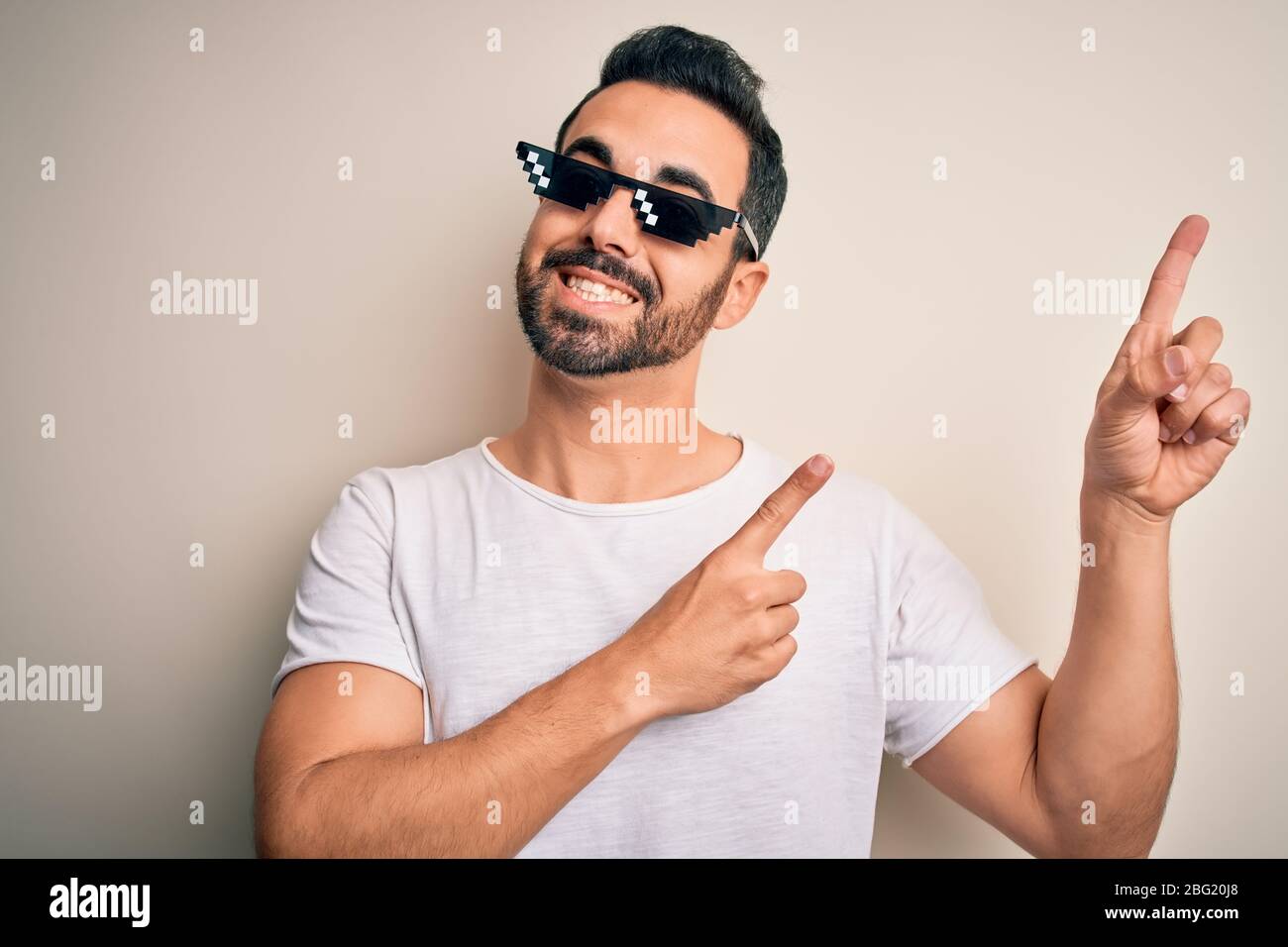 Young handsome man with beard wearing funny thug life sunglasses over ...