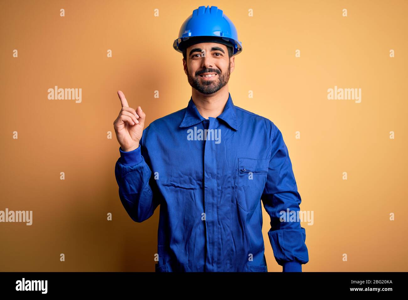 Mechanic man with beard wearing blue uniform and safety helmet over ...