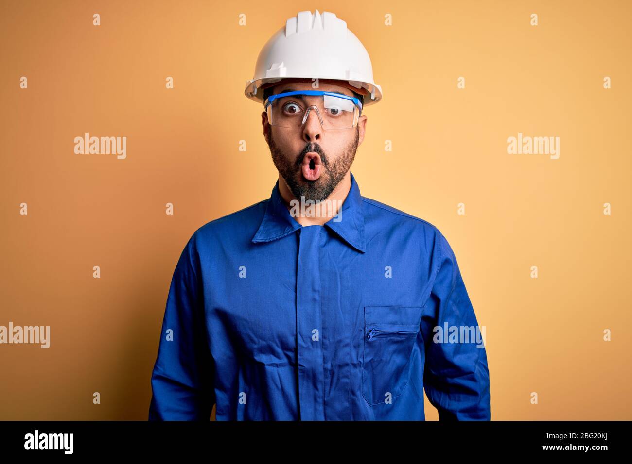 Mechanic man with beard wearing blue uniform and safety glasses over ...