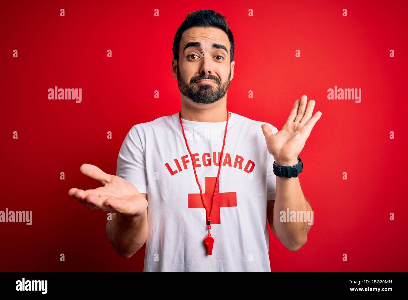 Young handsome lifeguard man with beard wearing whistle over isolated ...
