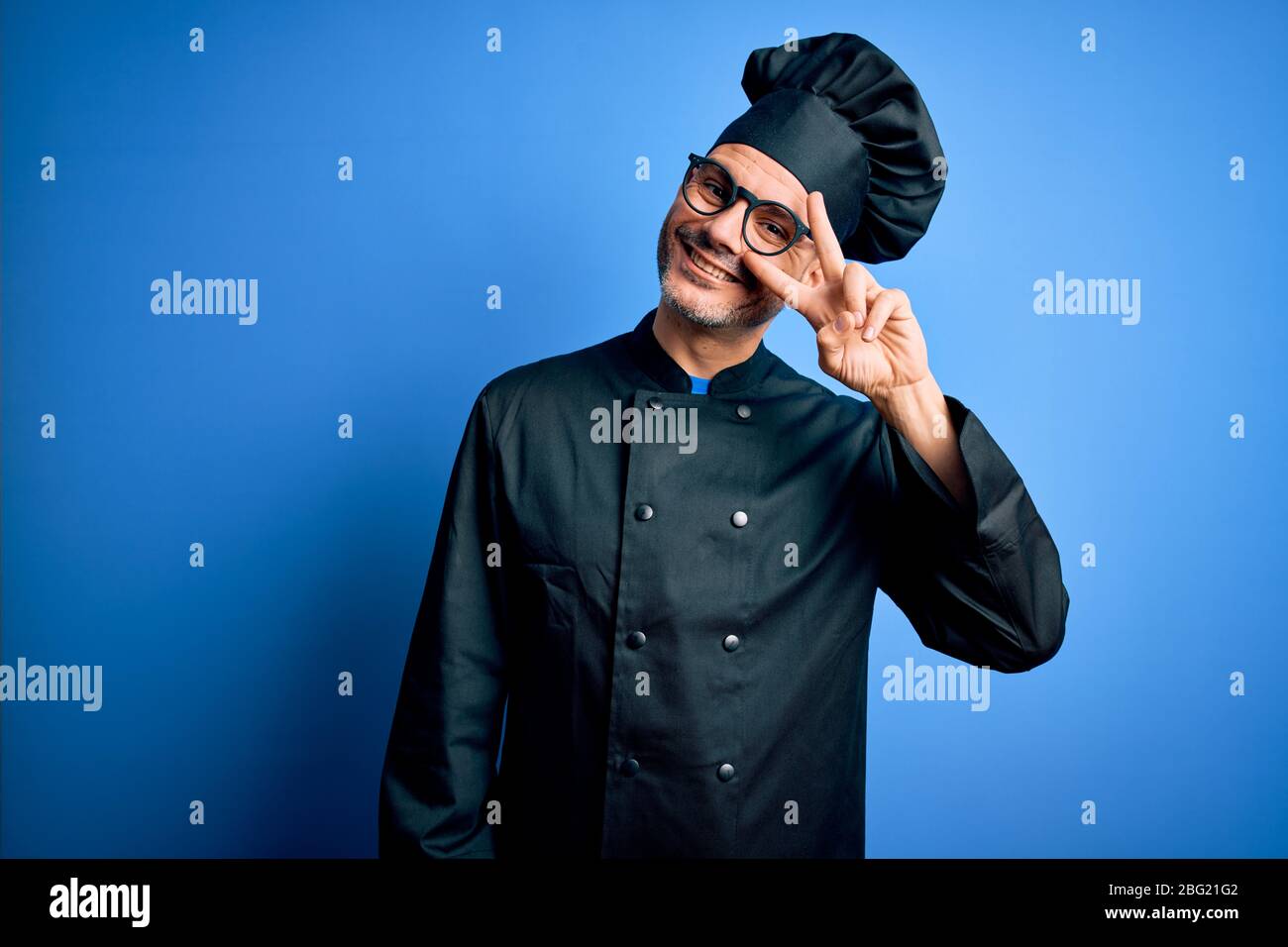 Young handsome chef man wearing cooker uniform and hat over isolated ...