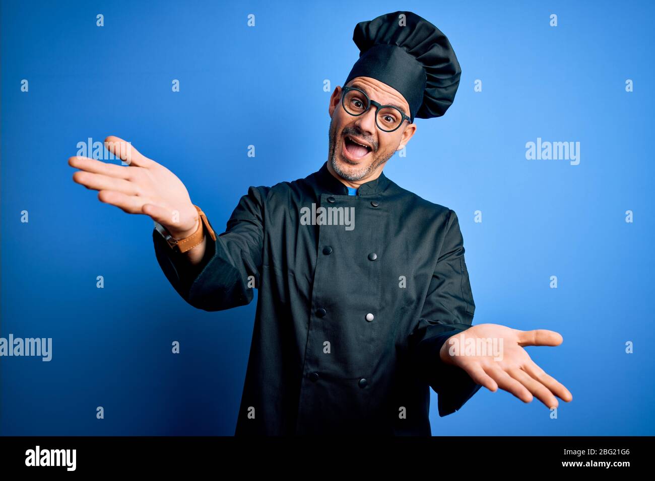 Young handsome chef man wearing cooker uniform and hat over isolated ...
