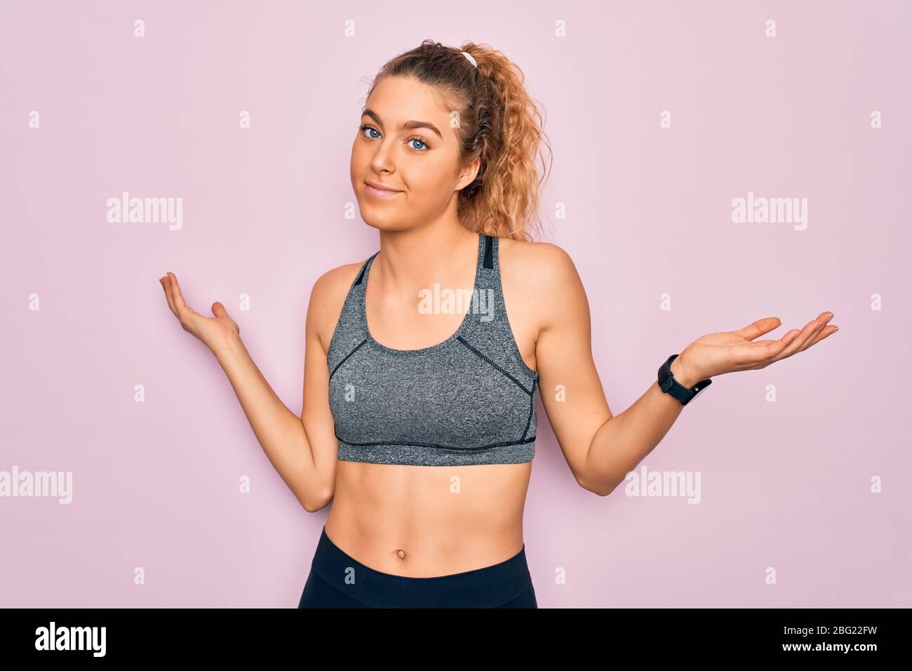 Young beautiful blonde sportswoman with blue eyes doing exercise ...