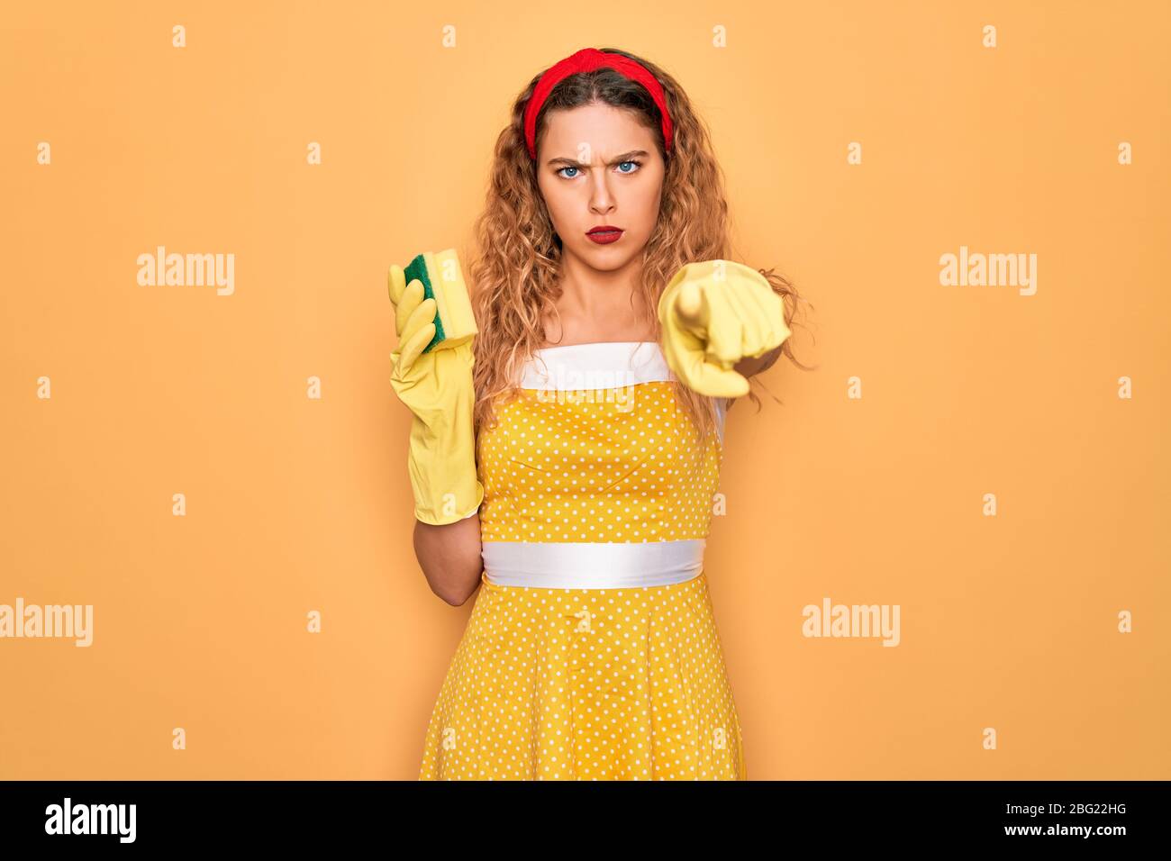 Young beautiful blonde woman with blue eyes cleaning using gloves and ...
