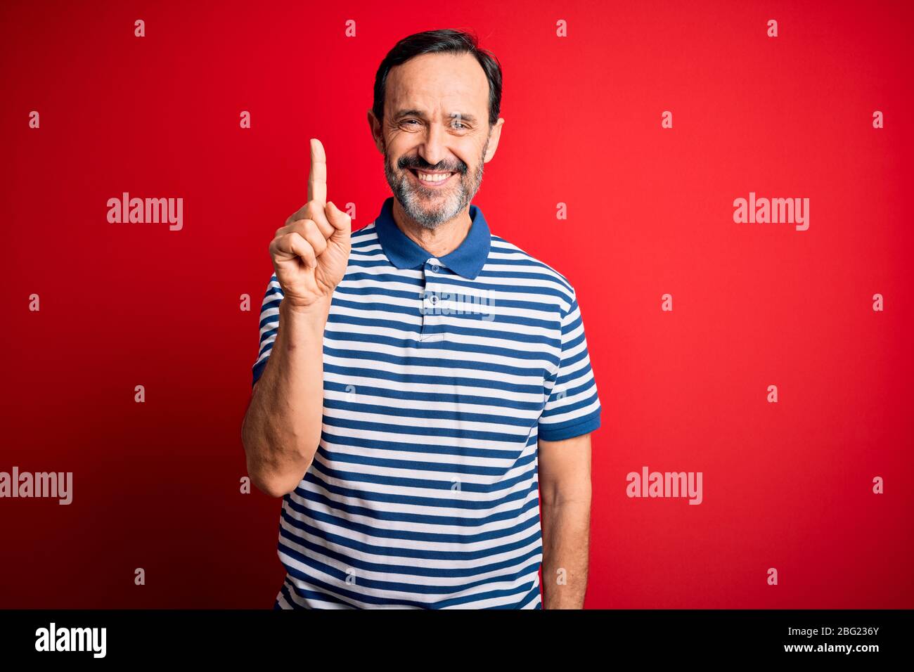 Middle age hoary man wearing casual striped polo standing over isolated ...