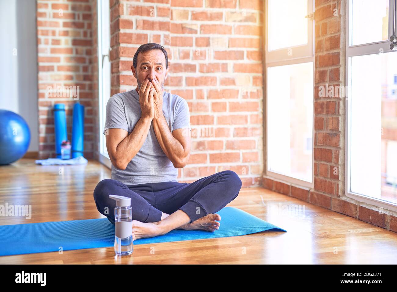 Middle age handsome sportman sitting on mat doing stretching yoga ...