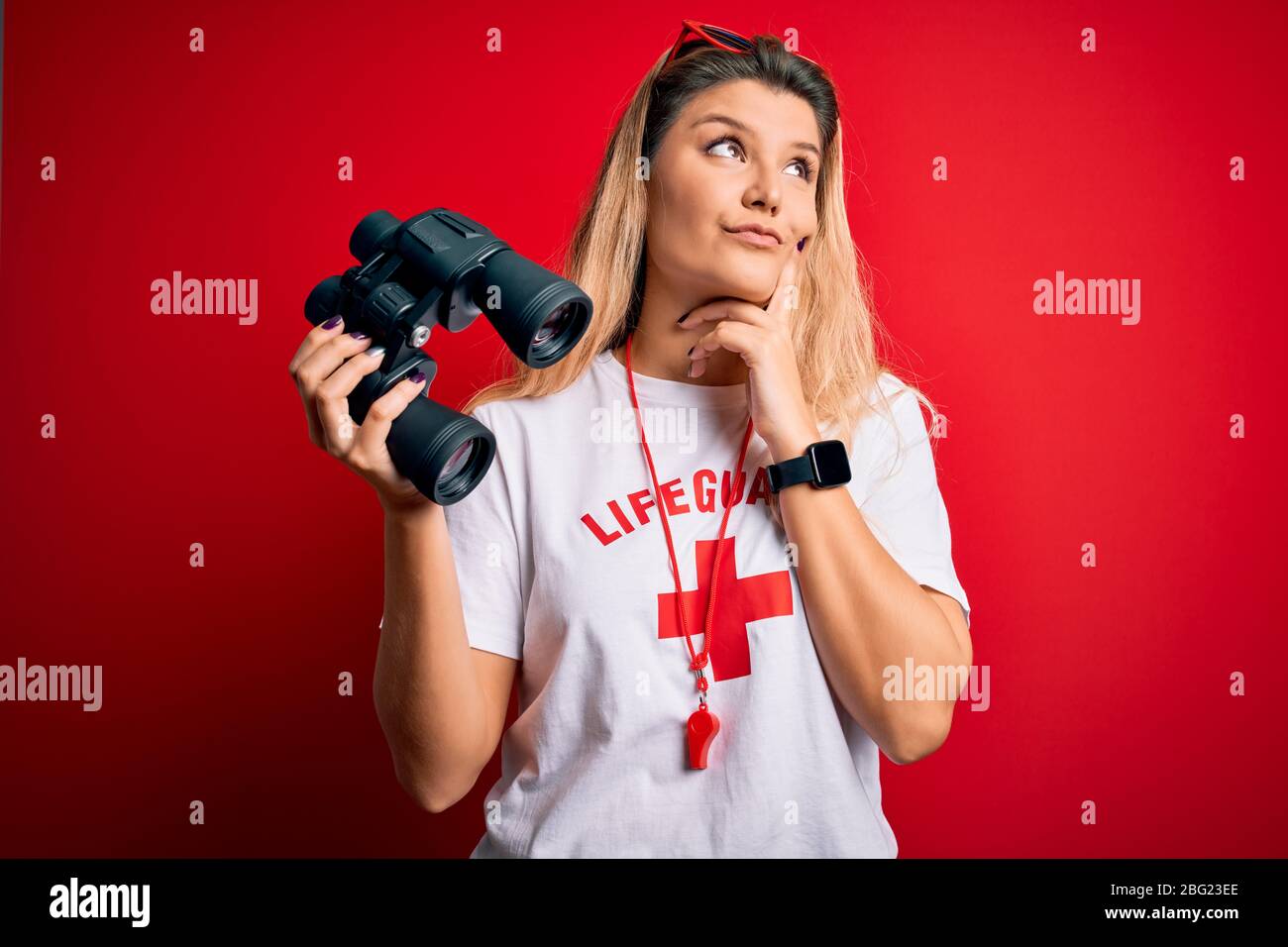 Young beautiful blonde lifeguard woman using binoculars and whistle ...