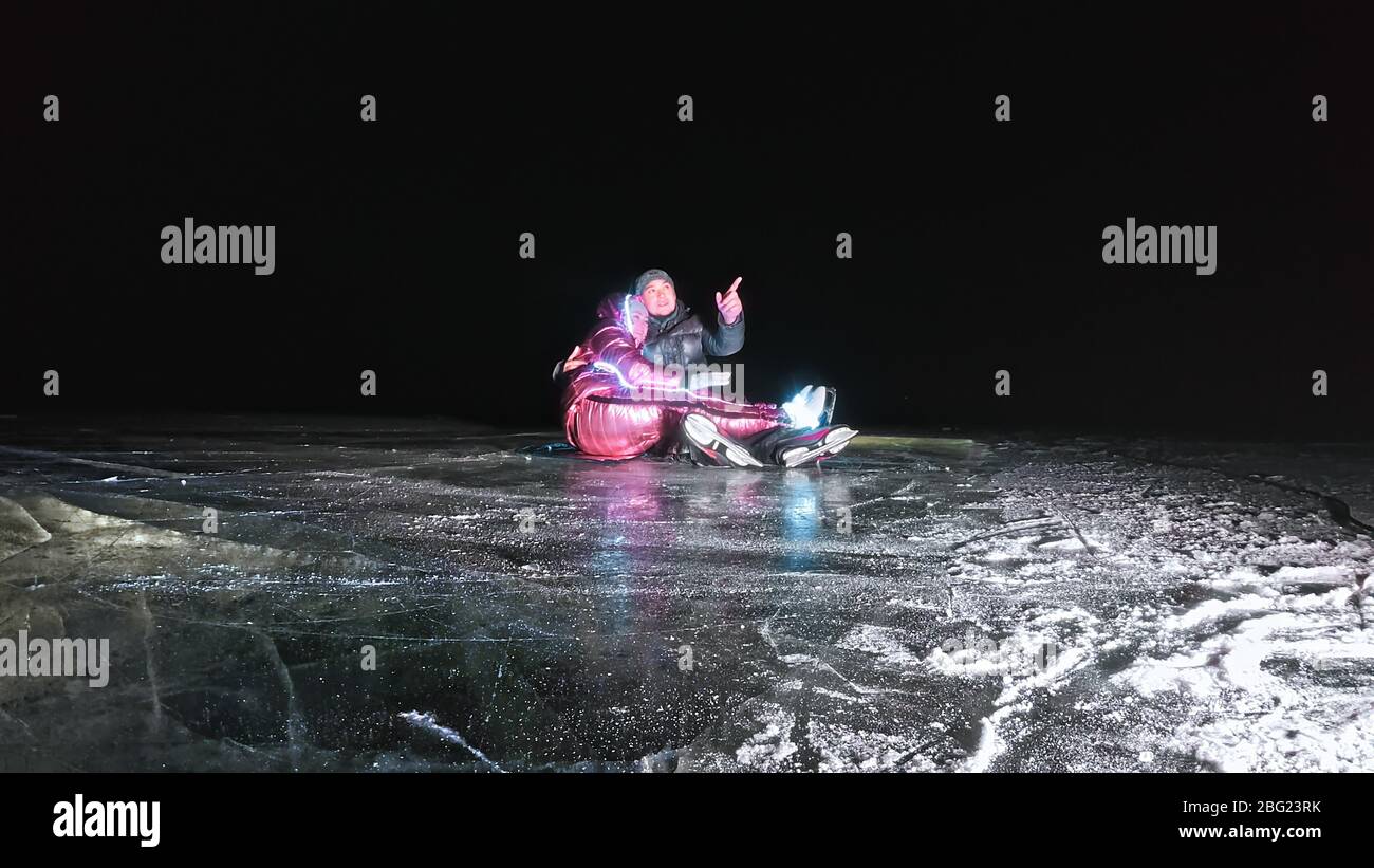Young loving couple skating at ice rink at night. Man and woman kiss ...