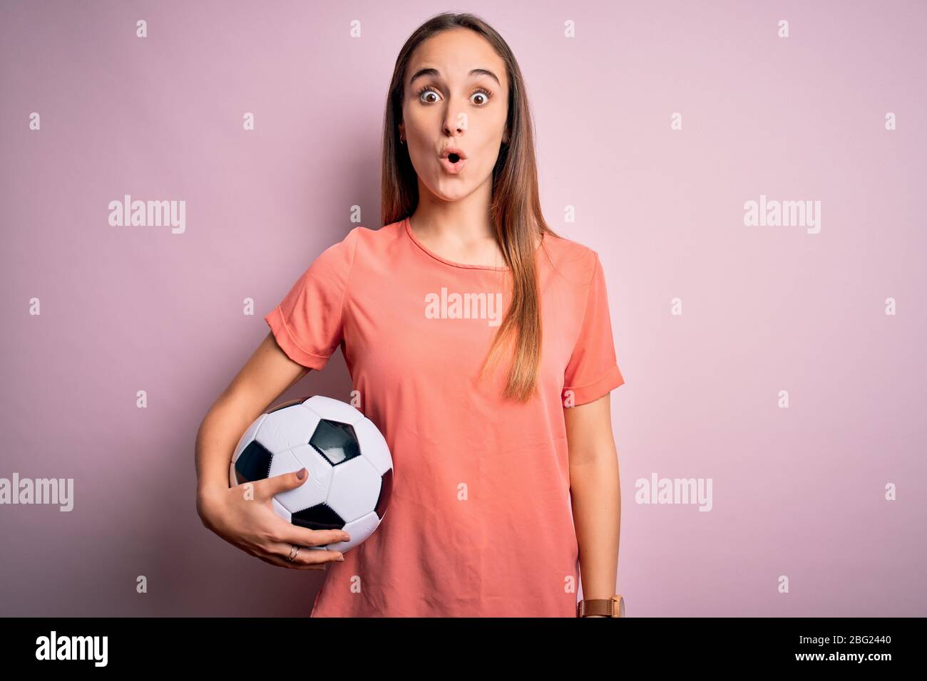 Young beautiful player woman playing soccer holding football ball over ...
