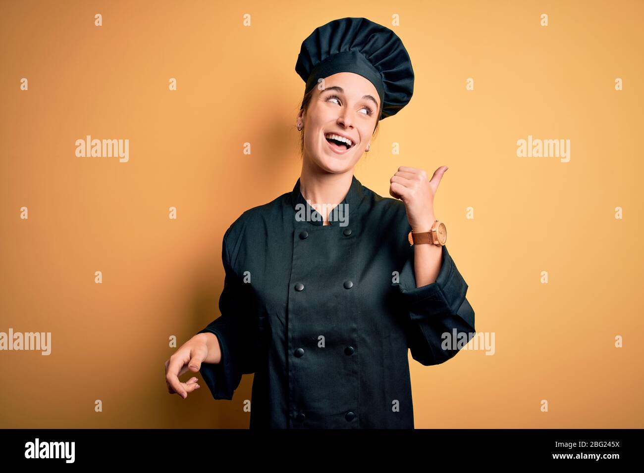 Young beautiful chef woman wearing cooker uniform and hat standing over ...