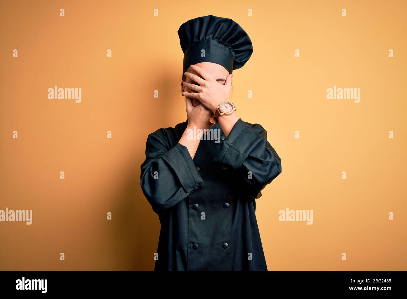Young beautiful chef woman wearing cooker uniform and hat standing over ...