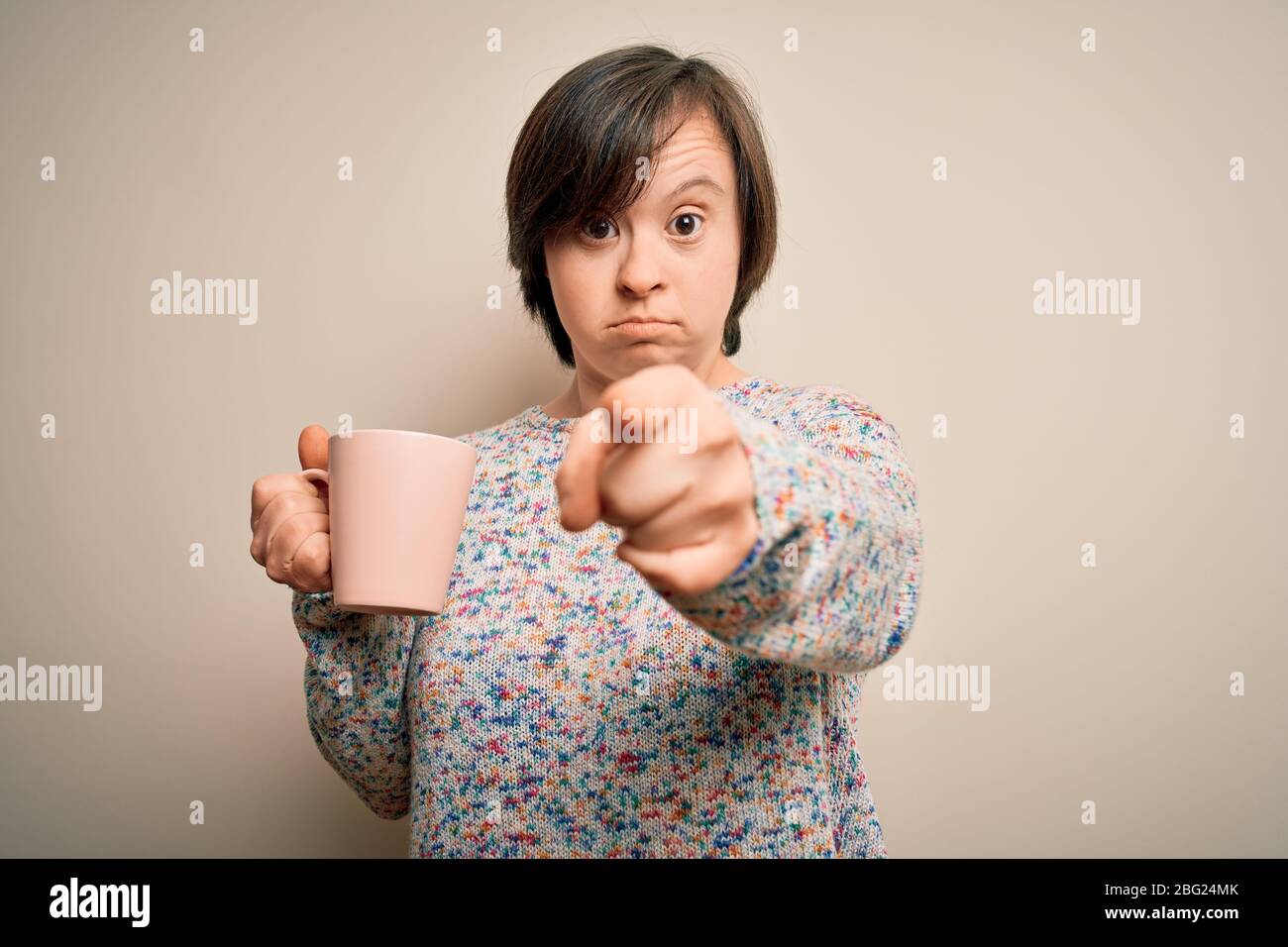 Young down syndrome woman drinking a cup of hot coffee over isolated ...