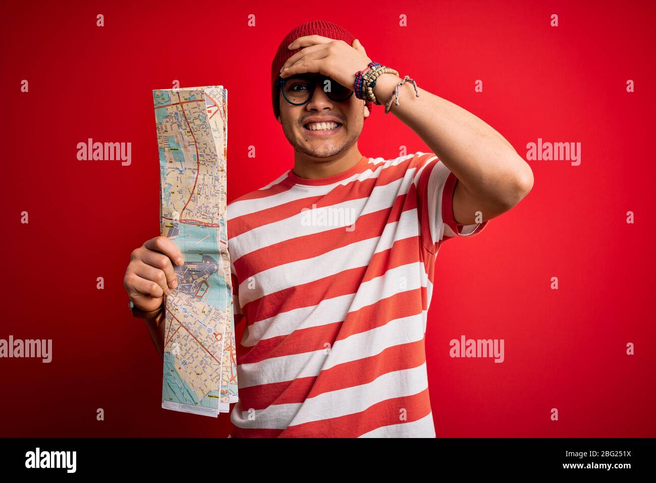 Young brazilian tourist man on vacation holding city map over isolated ...