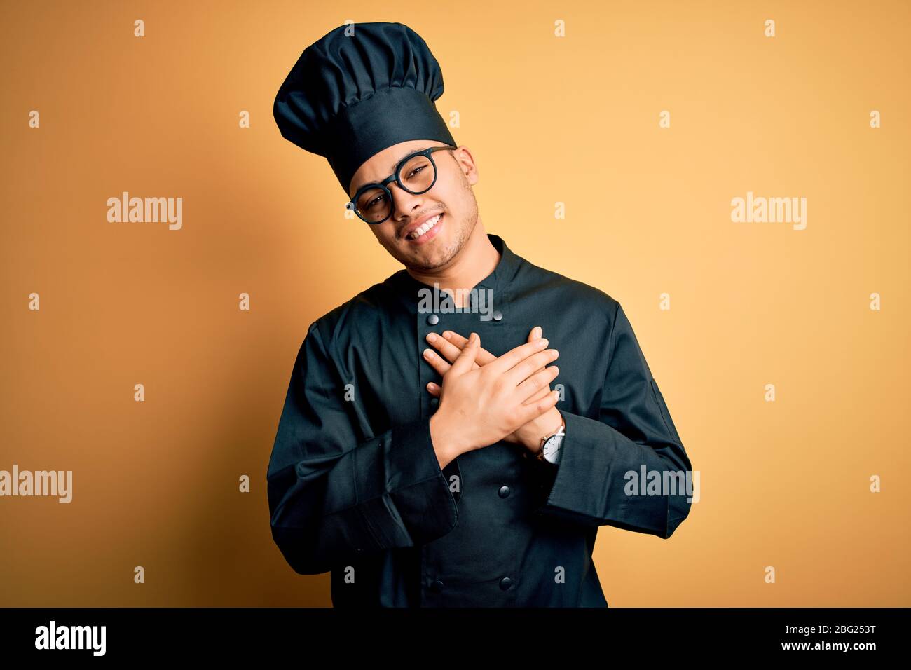 Young brazilian chef man wearing cooker uniform and hat over isolated ...