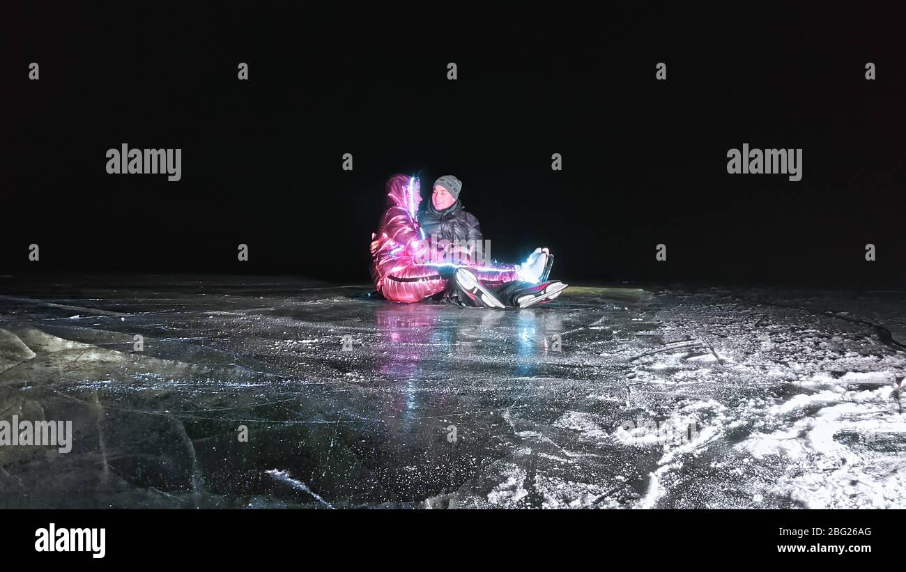 Young loving couple skating at ice rink at night. Man and woman kiss ...