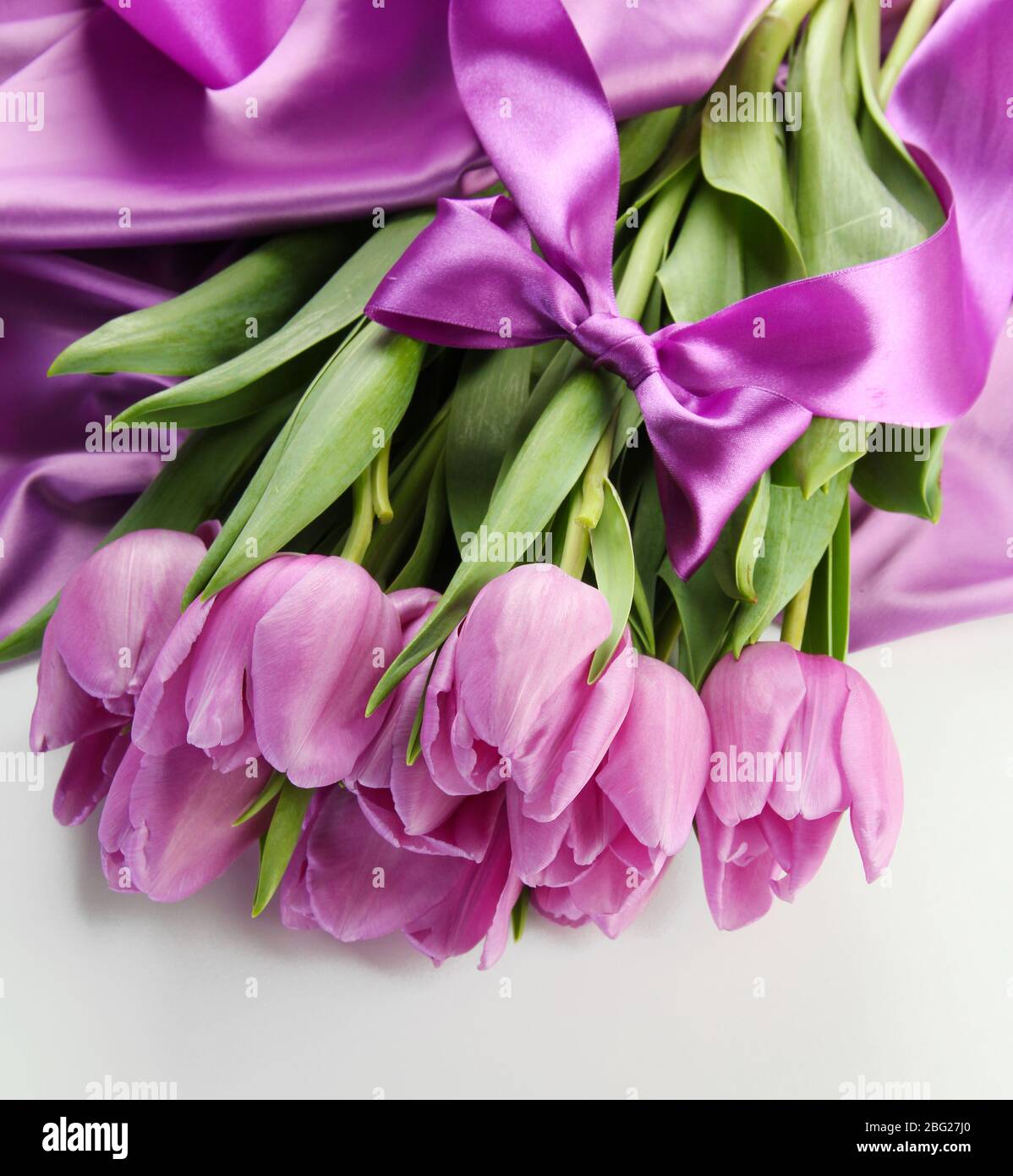 Beautiful bouquet of purple tulips on satin cloth, isolated on white ...