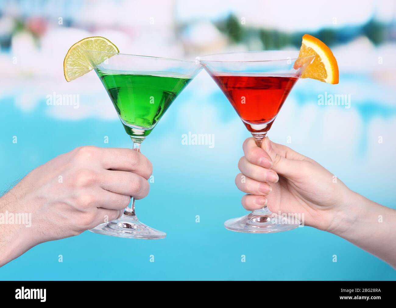Cocktails in men's and women's hands on pool background Stock Photo - Alamy