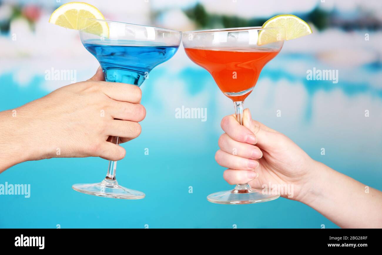 Cocktails in men's and women's hands on pool background Stock Photo - Alamy