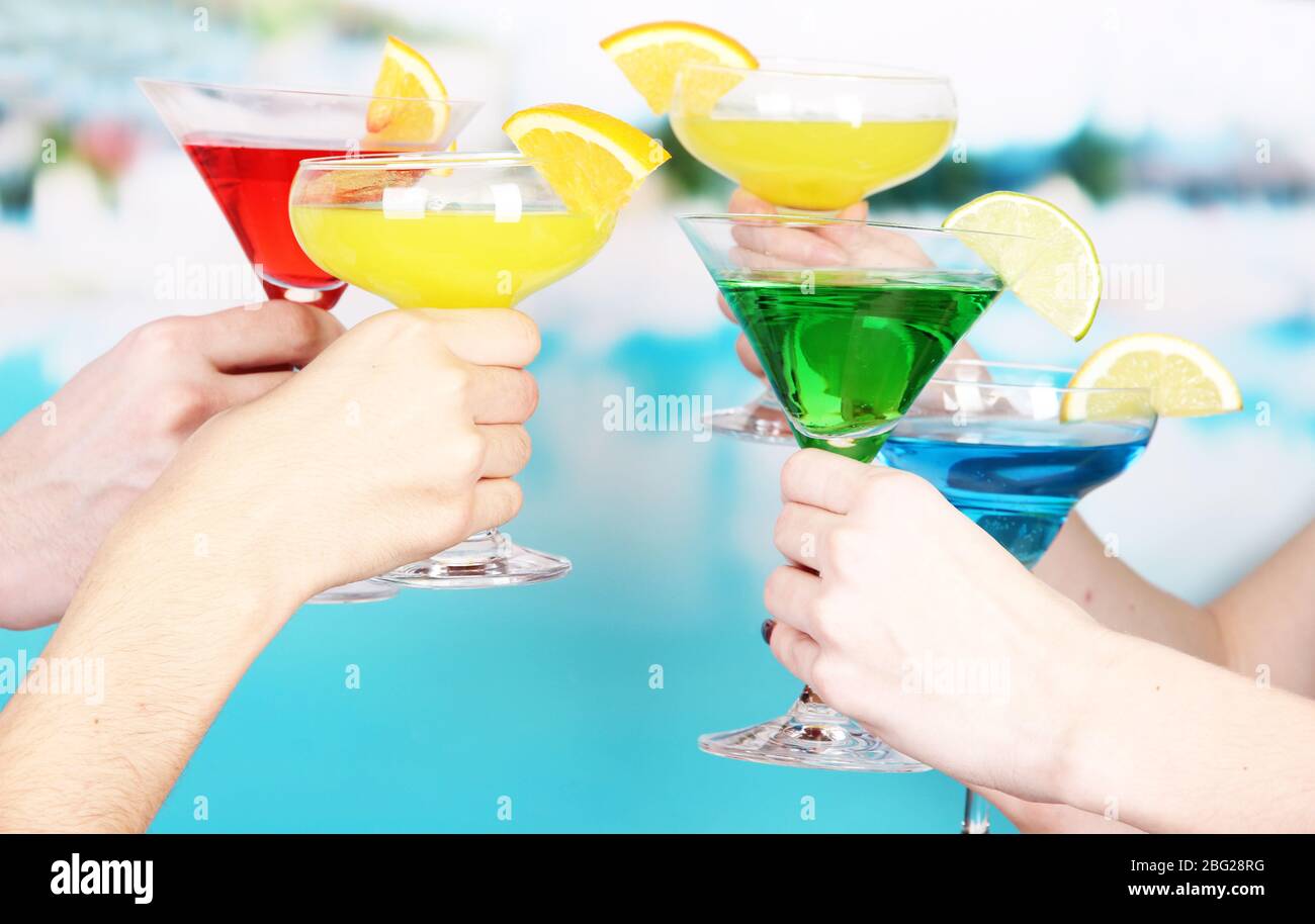 Cocktails in hands on pool background Stock Photo - Alamy