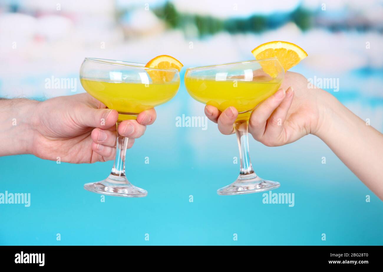 Cocktails in men's and women's hands on pool background Stock Photo - Alamy